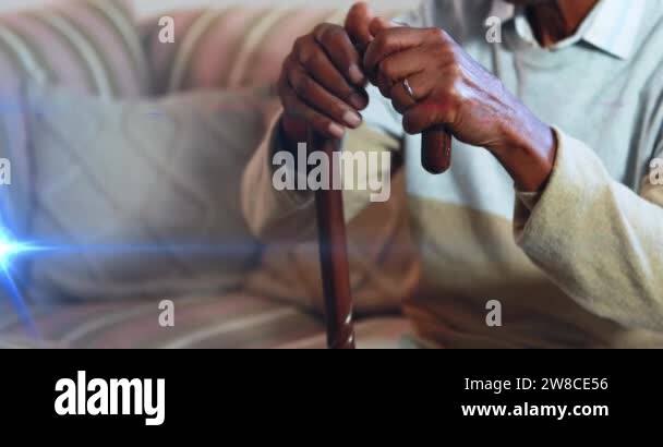 Animation of light moving over senior asian man at home on couch using ...