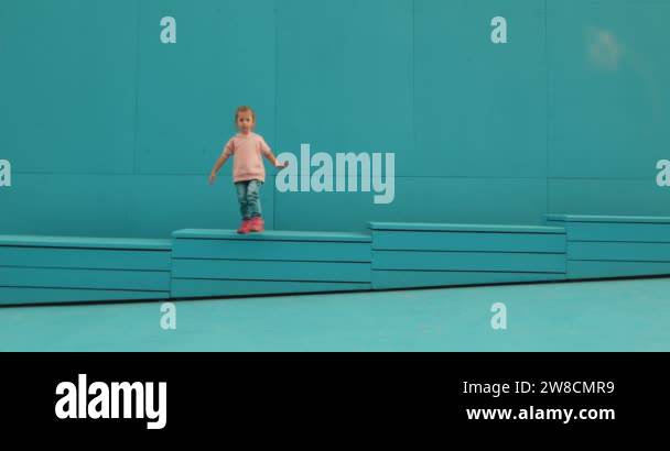Cute shy little girl kid dancing outside on blue background. Funny ...