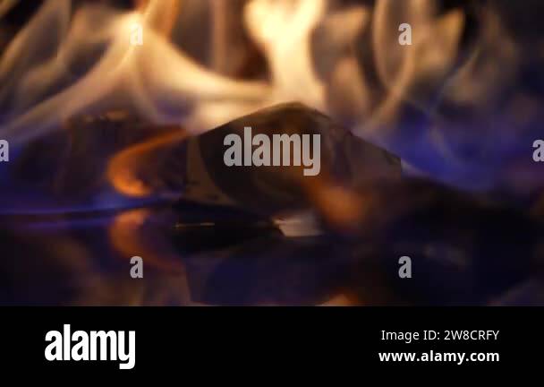 Flare and ignition of fire illuminating crumpled paper dollar bills ...