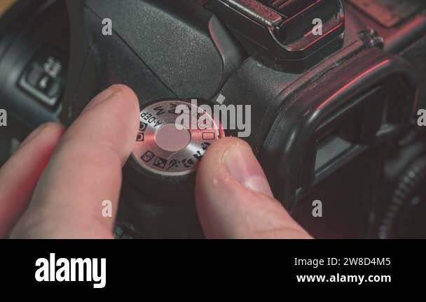 Man turning Canon DSLR camera settings mode dial wheel to the M manual mode from the full ...