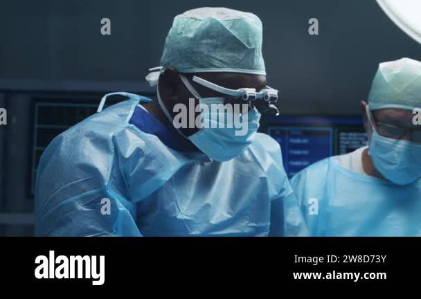Multiracial team of professional medical surgeons performs the surgical ...