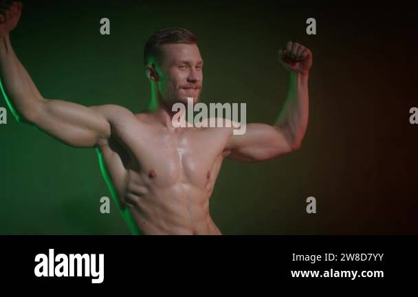 A sportsman with a bare body is standing in a pose to show the biceps ...