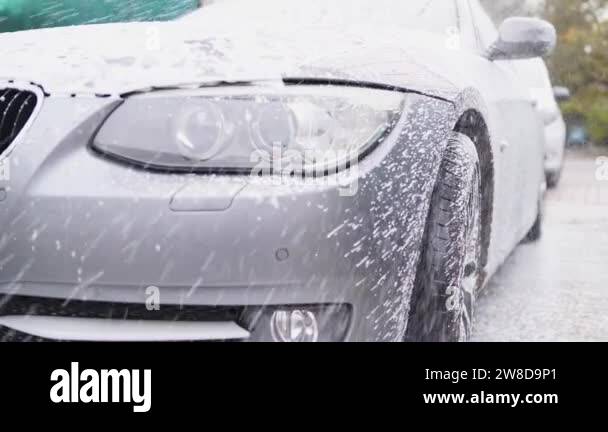 washing a gray bmw car under the pressure of white foam on the street ...