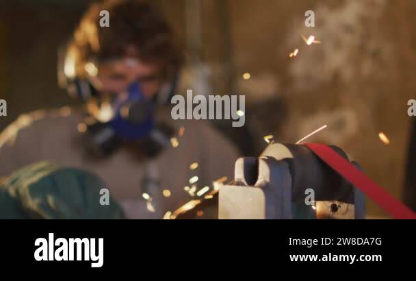 Caucasian male blacksmith wearing breathing mask and ear guards ...
