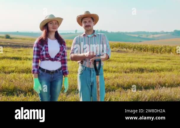 Happy young female and male farmers in hat rejoicing and looking at the ...