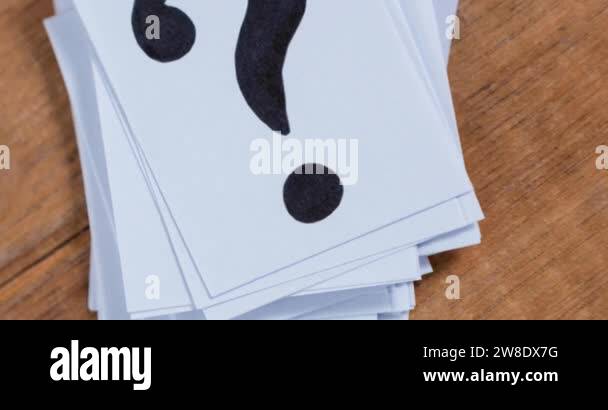Stack of white sheets of paper with question mark signs on wooden table ...