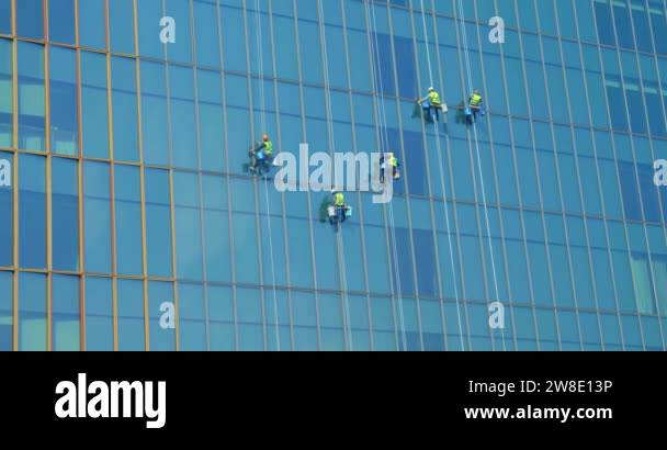 Five men workers in red and yellow work clothes cleaning the exterior ...