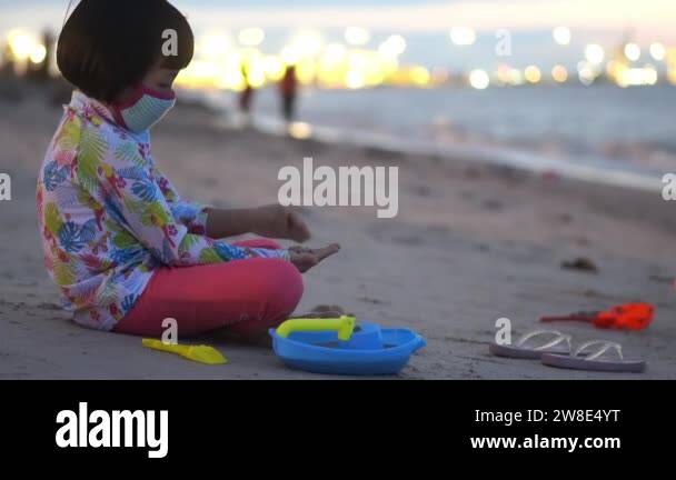 Selective focus chinese little girl wear face mask play at beach in ...