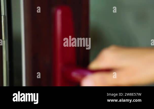 A woman's hand opens and closes a plastic door with a push handle. A ...