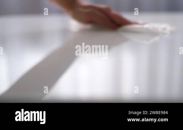 Woman cleaning and polishing the kitchen worktop with a spray detergent ...