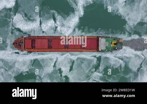Aerial above epic huge steel icebreaker breaks ice by bow of ship and ...
