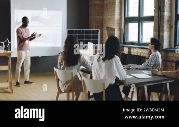 African American engineer pointing at slide on whiteboard and ...