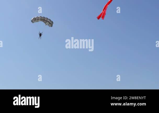 Parachutist with an open parachute is flying and slows down for landing ...