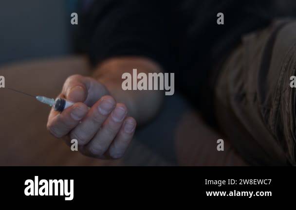 Drug addict man lying on sofa holding syringe. Overdosed man lying on ...