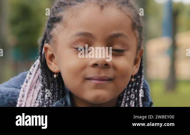 Close-up portrait african american little kid thoughtfully looking at camera sligh smiling cute ...