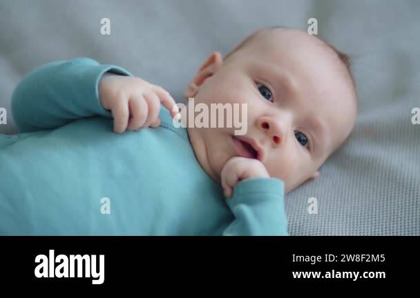 Cute two-month-old baby in blue clothes looks into camera, slow motion ...