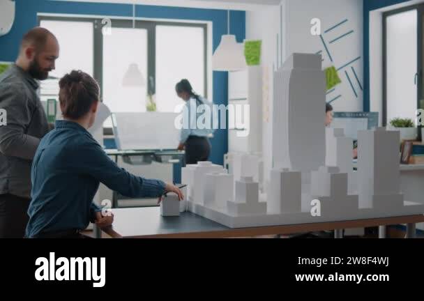 Man And Woman Analyzing Blueprints Plan And Building Model To Design Urban Construction Stock