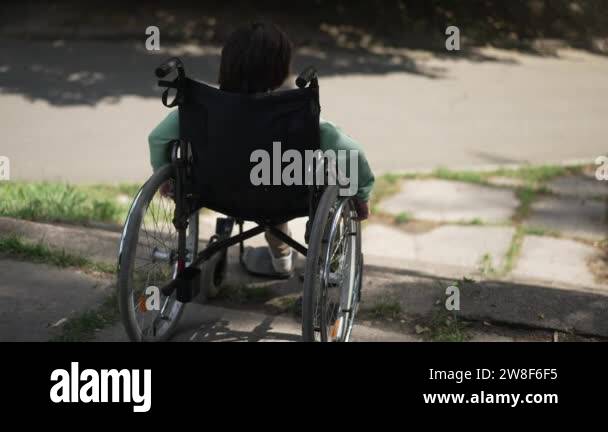Back view disabled boy in wheelchair outdoors on sunny day at stairs ...