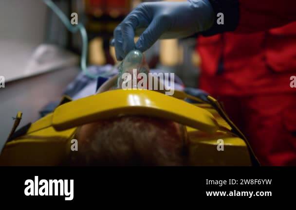 Paramedic hand in glove holding oxygen mask on patient face in ...