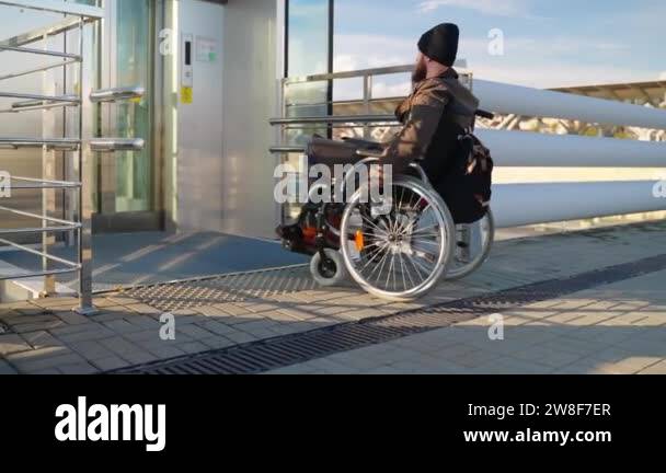 paraplegic man in manual wheelchair is using lift for disabled people ...