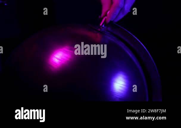 Female hand spinning around globe under colored neon light in the dark ...