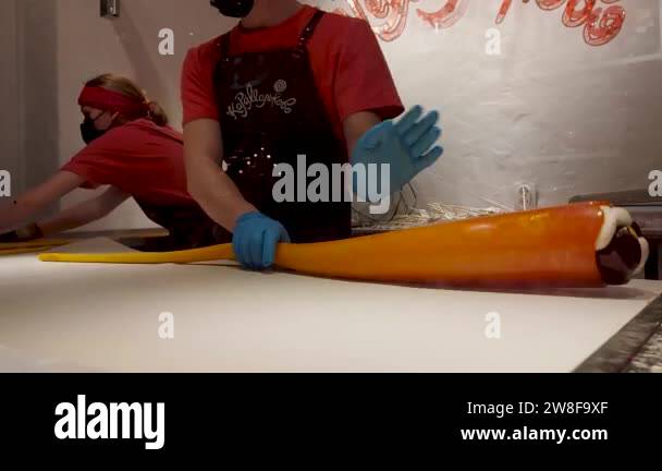 Candy sticks in the cooking process. A pastry chef rolls a caramel ...