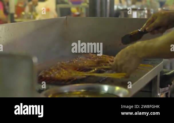Asian man making chicken wings on a griddle at a night market in Kuala ...
