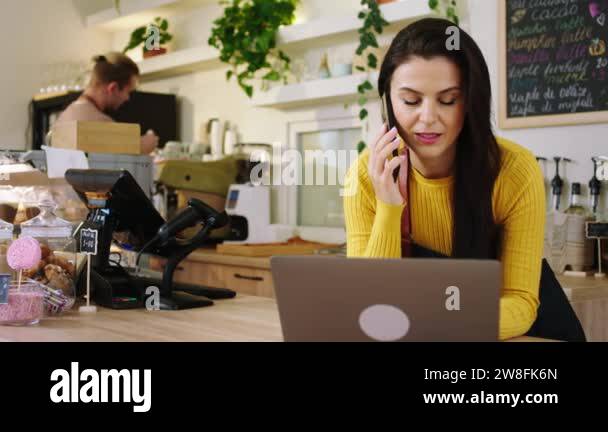 Charismatic with a large smile woman barista speaking on the smartphone ...