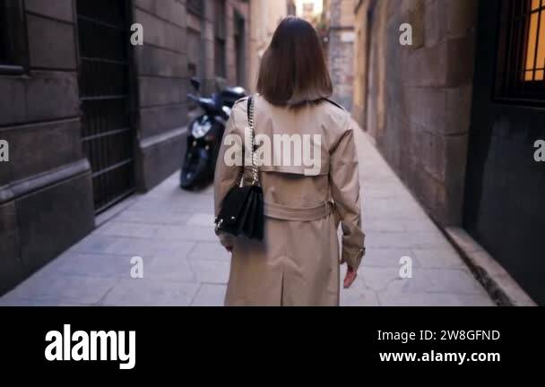 Unrecognizable stranger woman walking alone in empty narrow street ...