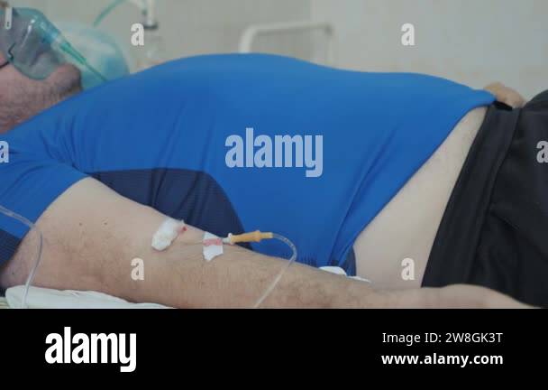 Sick man in a hospital bed. An intravenous drip is installed in the arm ...