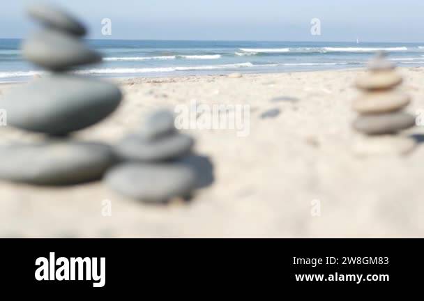 Rock balancing on ocean beach, stones stacking by sea water waves ...