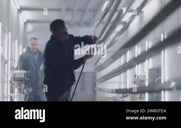 Two men at work in the paint shop. Molar workshop and worker processes steel profiles from dust ...