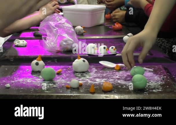 Close up of hands of woman and children. Teacher is teaching kids creativity, they are modelling ...