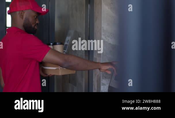 Courier african man doing fast food delivery, dials the house number in ...