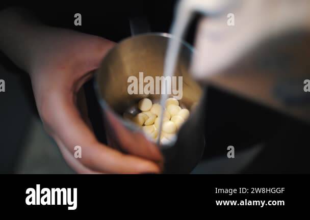 making milk drink. close-up. barista pours milk into pitcher, add to ...