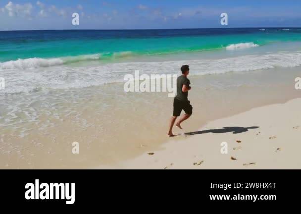 Back view of a runner man running on the beach Stock Video Footage - Alamy