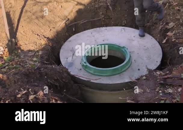 A worker installs a sewer manhole on a septic tank made of concrete ...