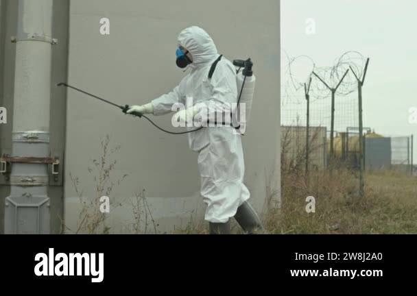 Slowmo shot of male ecologist in protective coverall spraying ...