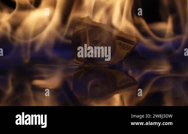 Flare and ignition of fire illuminating crumpled paper dollar bills ...