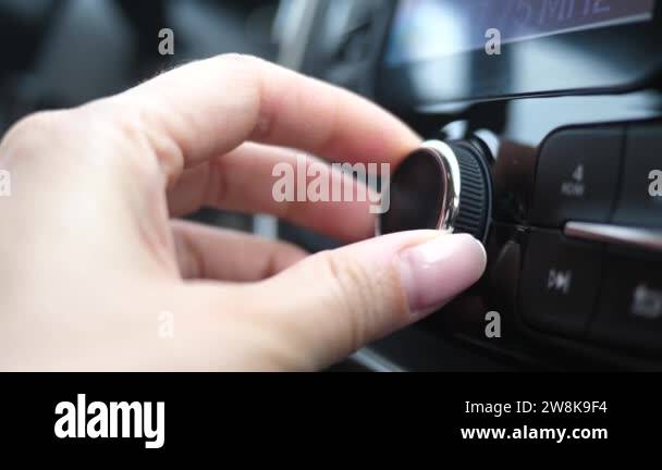 The male hand adjusts tuning of car radio. The driver turns up volume ...