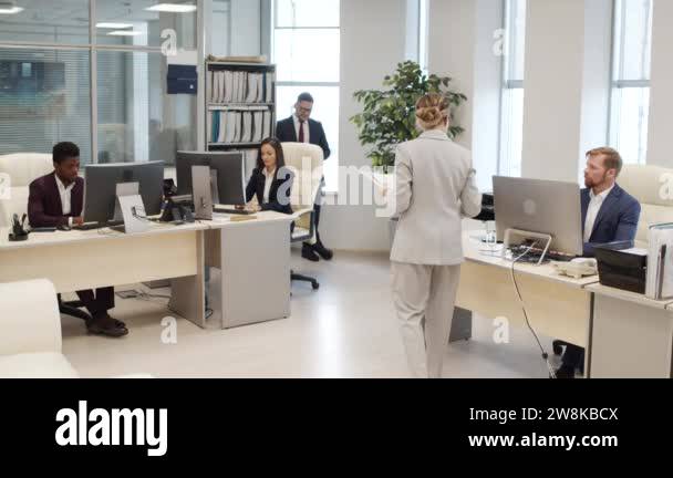 Tracking shot of serious female secretary in suit leaving documents on ...