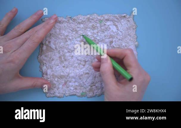 Womens hands draw a sign of reuse with a green felt-tip pen. Drawing on ...