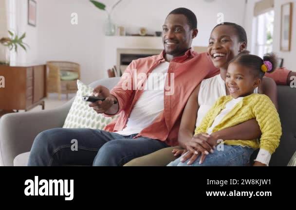 Relaxed african american family watching TV together. Happy mature father changing television ...