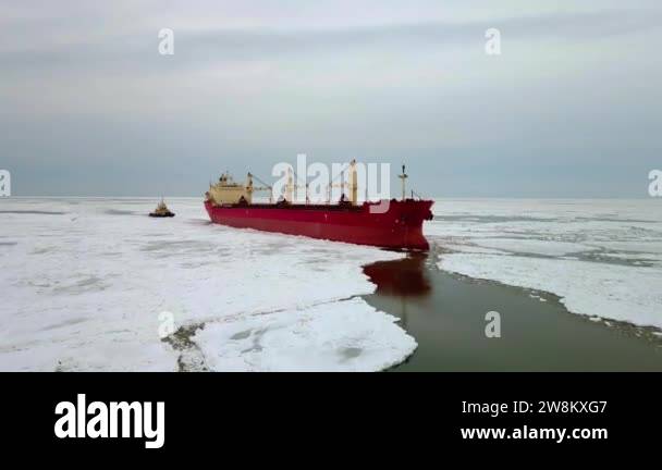Aerial above epic huge steel icebreaker breaks ice by bow of ship and ...