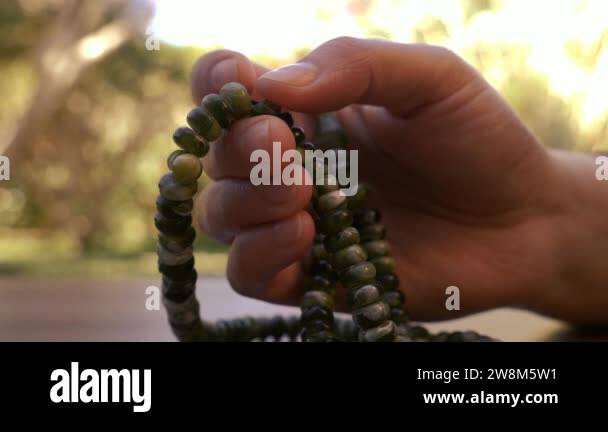 Woman is praying, repeating or chanting a mantra with a japa mala ...