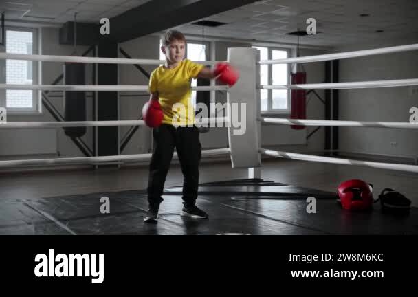 Little boy in boxing gloves kicking the air on the boxing ring then ...