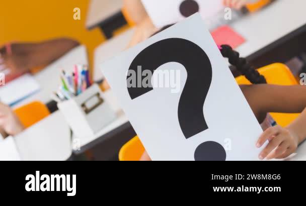 Diverse class of elementary schoolchildren at their desks holding ...