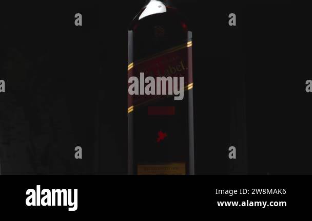 Johnnie Walker Red Label bottle on a dark background. The camera flies ...