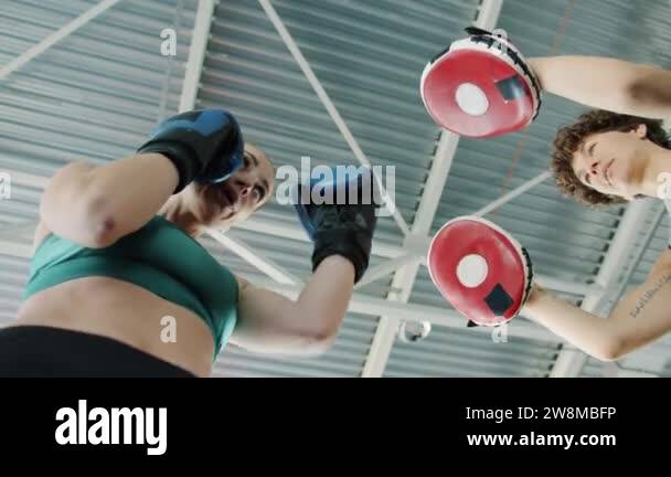 Low angle shot of young woman practising boxing moves with female ...