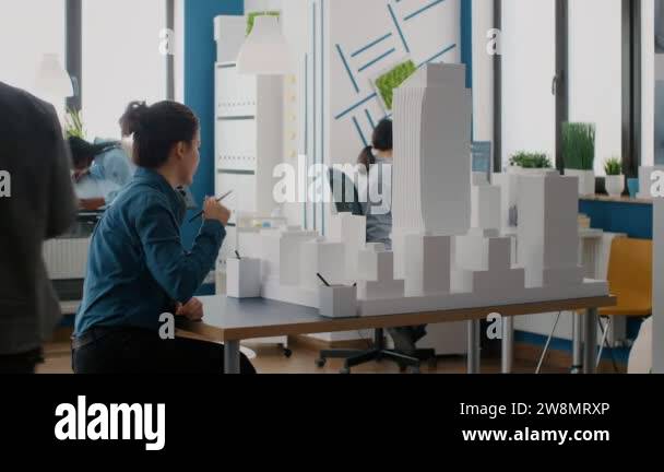 People working together to design blueprints plan with building model ...